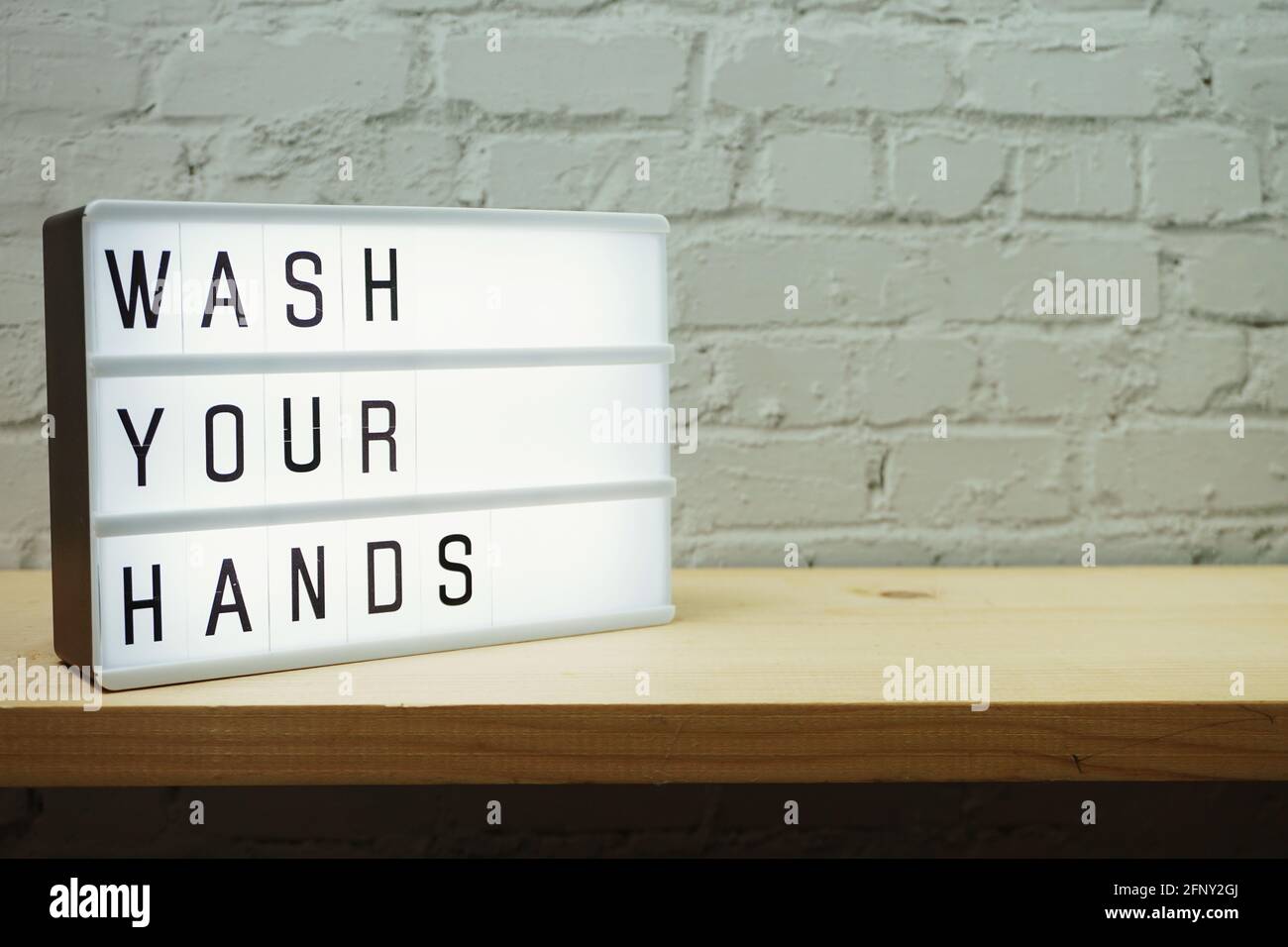 Wash Your Hands word in light box with space coy on white brick and ...