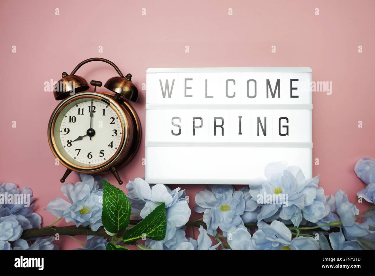 Welcome Spring text in light box and alarm clock with space copy on ...
