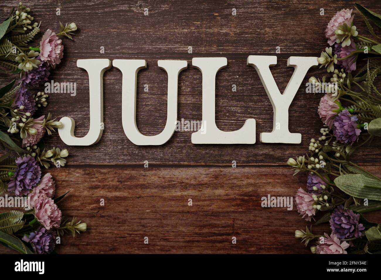 July alphabet letters with flower decoration on wooden background Stock ...