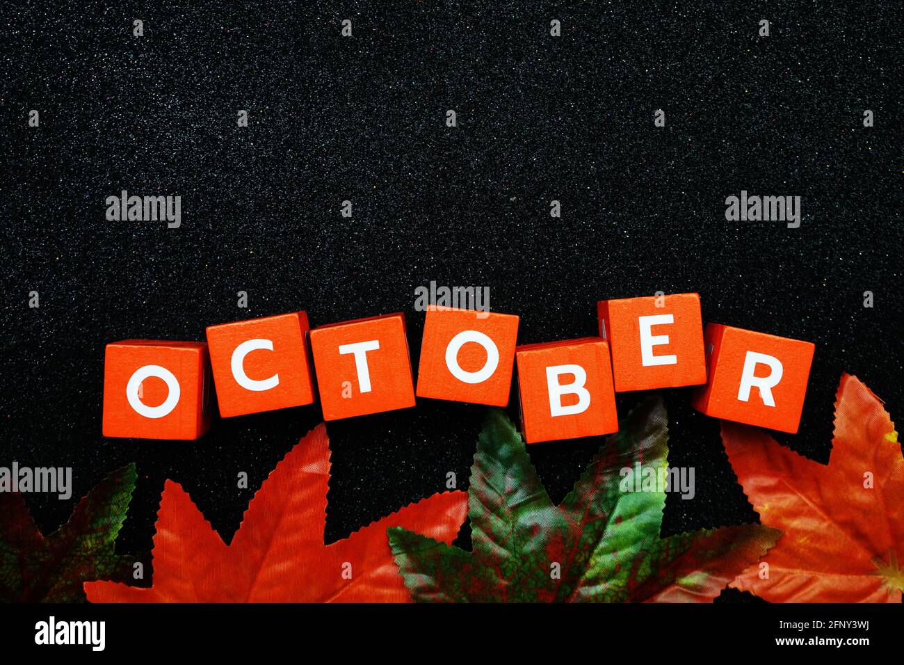 October alphabet letter with maple leave decoration on black glitter ...