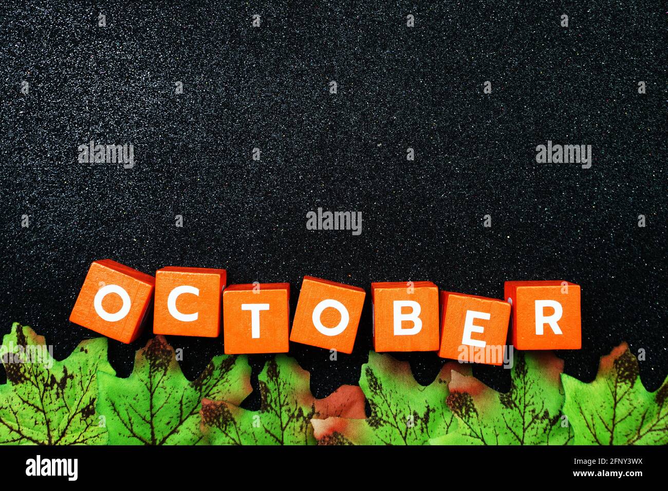 October alphabet letter with maple leave decoration on black glitter ...