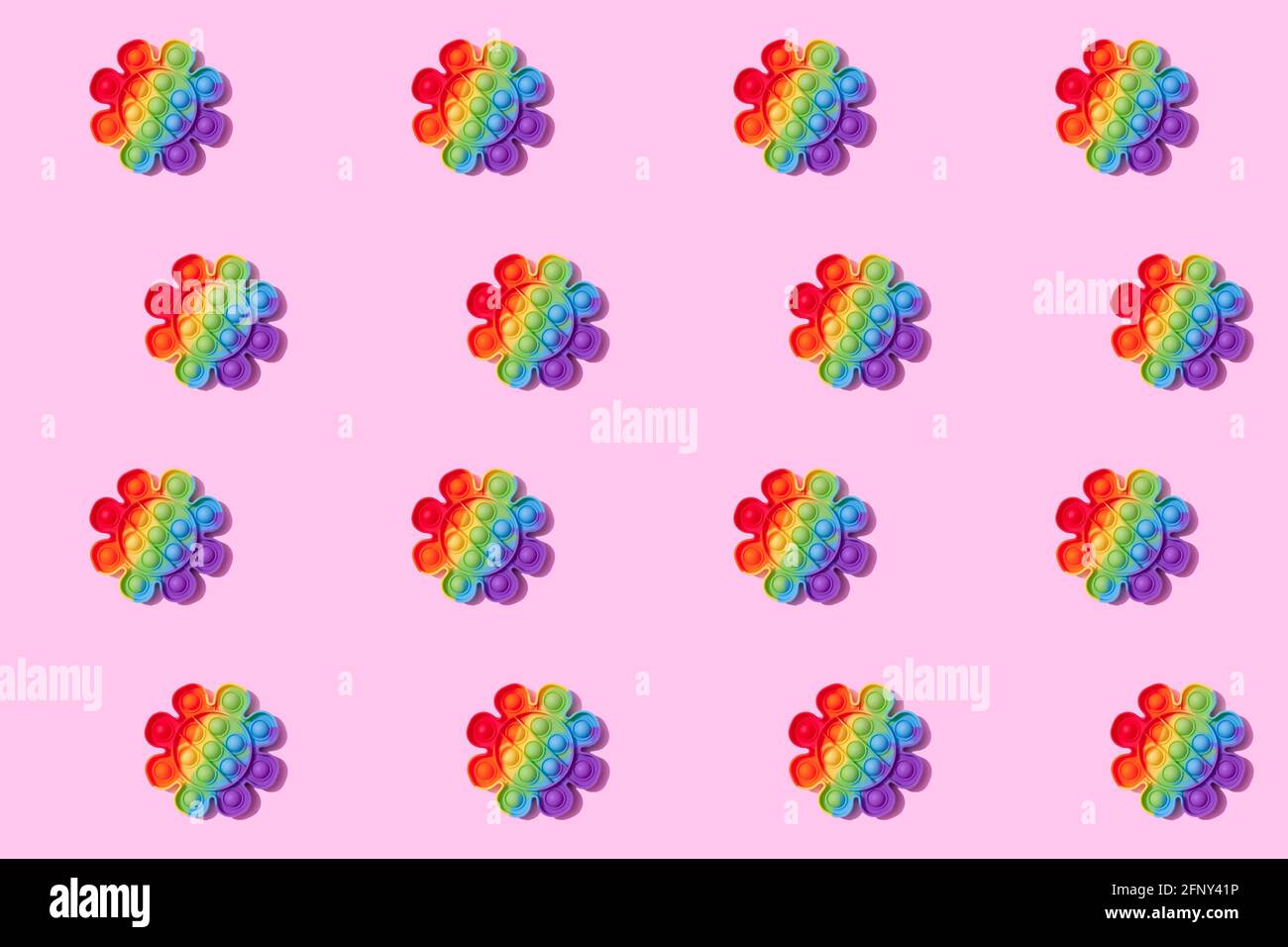Pattern made with rainbow pop it fidget toy on pink background. Push ...
