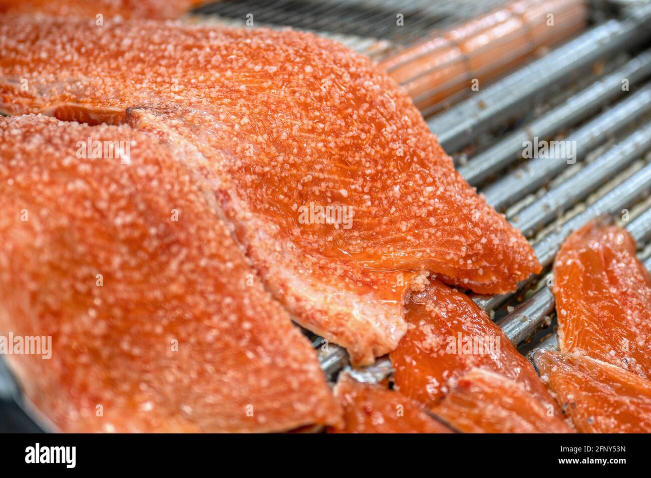 Many pieces of red fish fillet are lying on the conveyor. The fish is ...