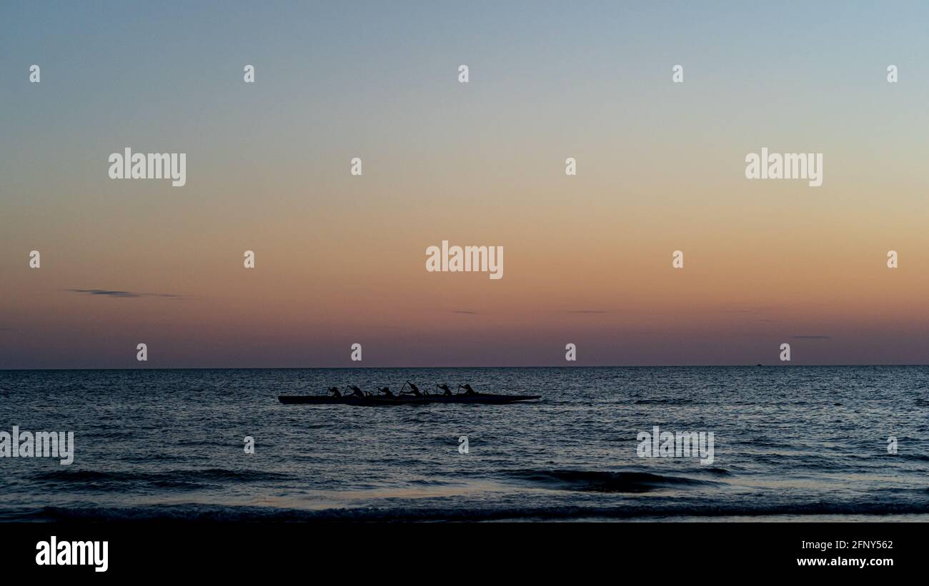Rowing crew in silhouette on water against pastel sunset sky Stock ...