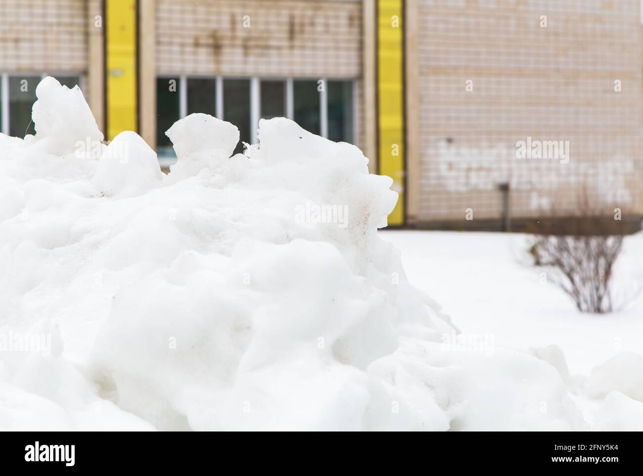 A large white snowdrift piled on a city street against the backdrop of ...