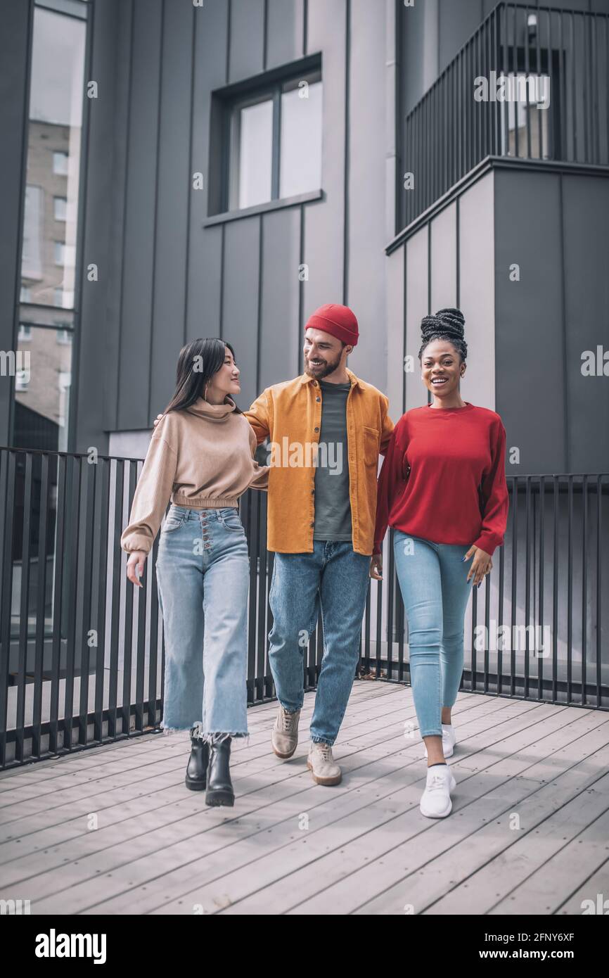 Three friends walking together and feeling good Stock Photo - Alamy