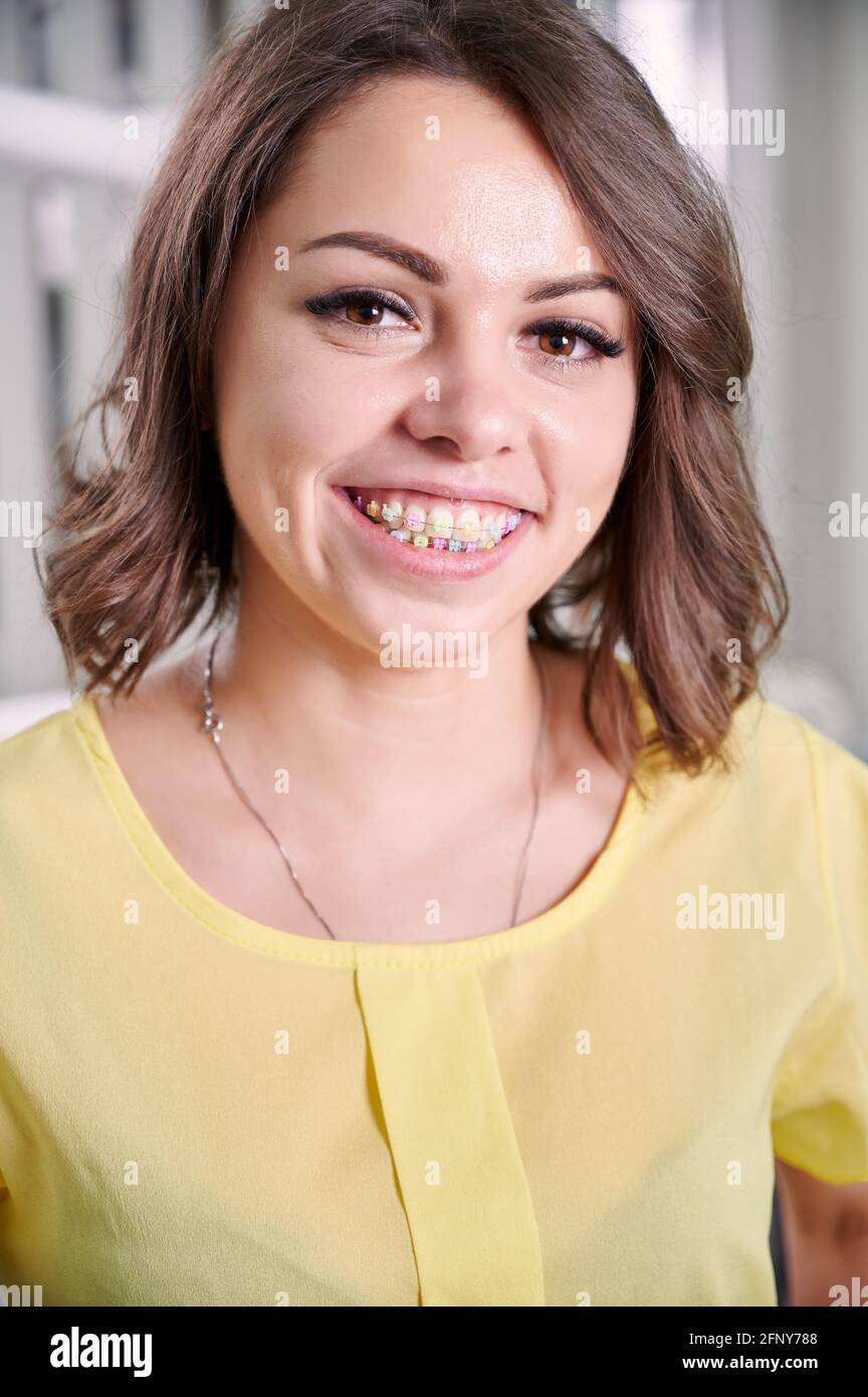 Portrait of cheerful woman with orthodontic brackets on teeth smiling ...