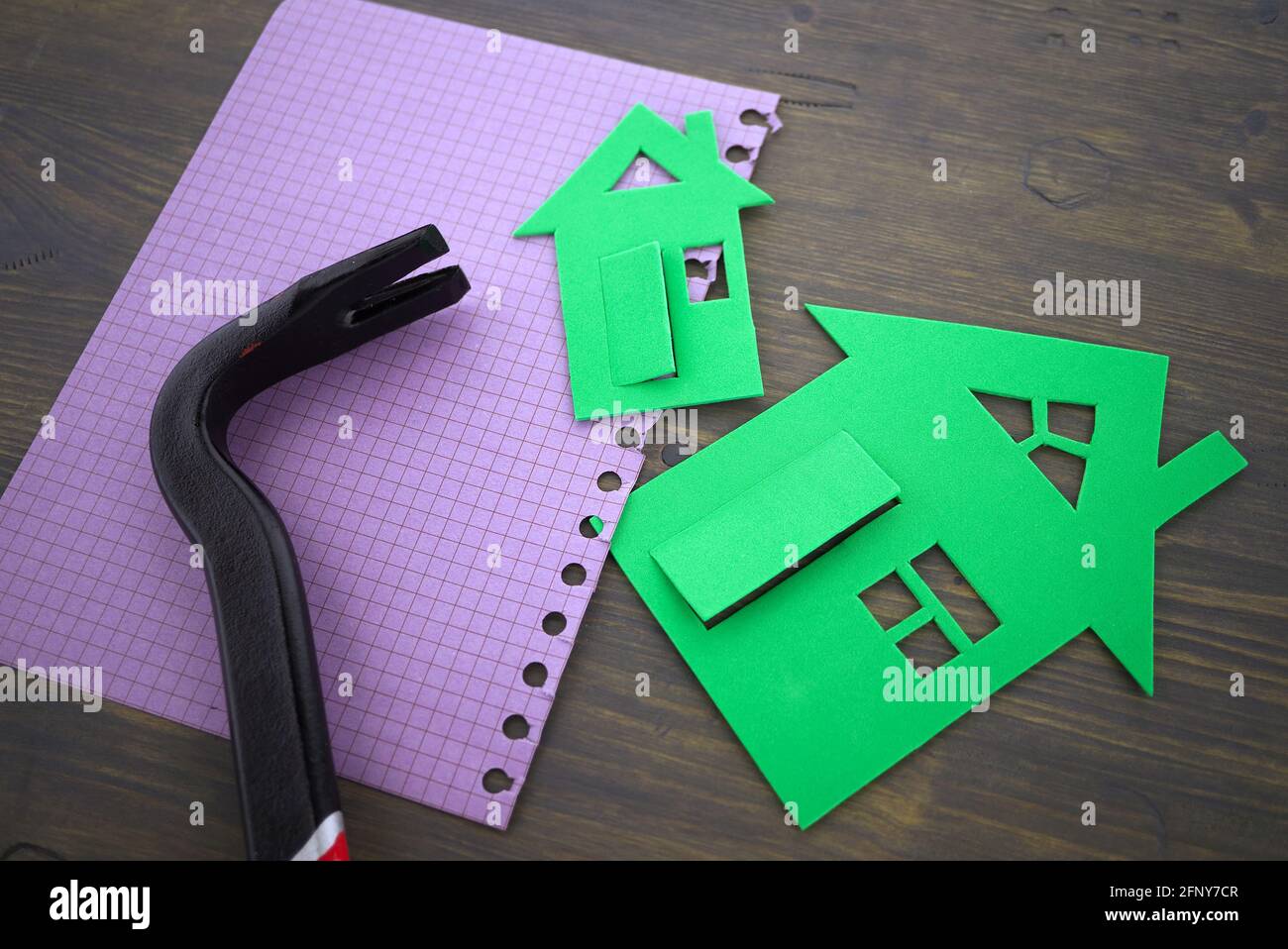 Green cutouts of model houses with hand tool on a memo notepad in a ...