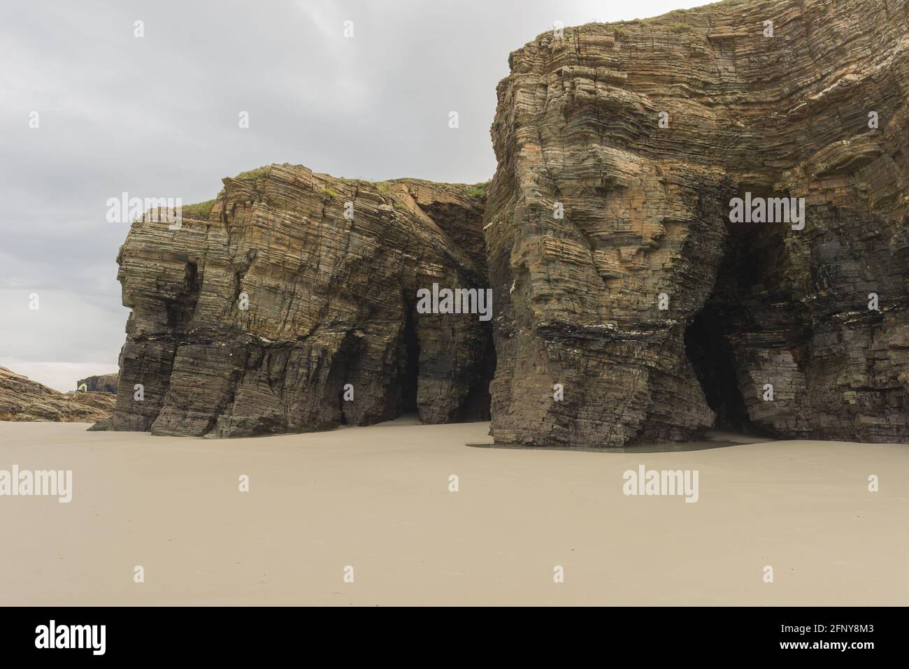 Giant natural rock formations on a sandy As Catedrais beach on a gloomy ...