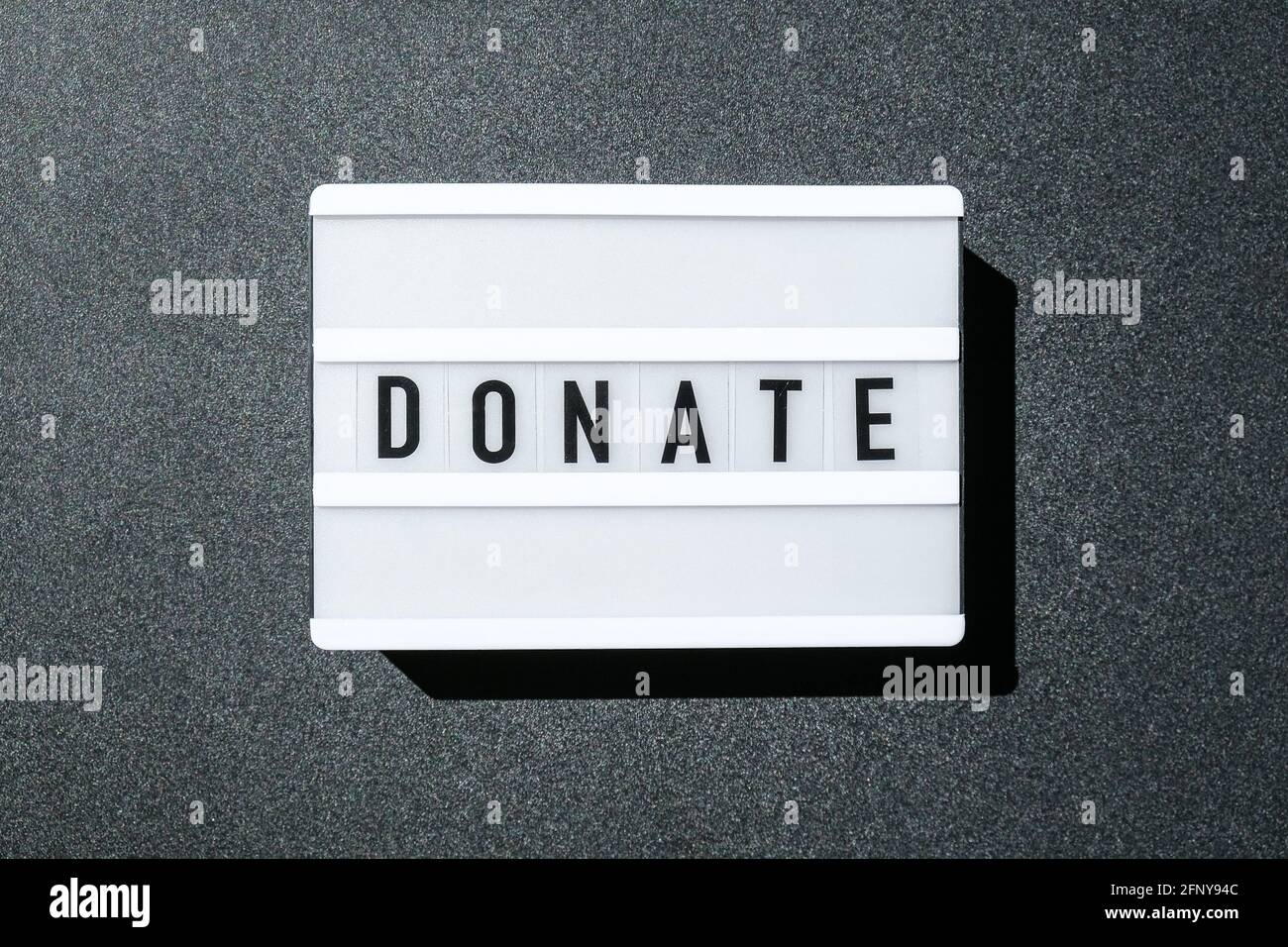 Lightbox board on a black background with the words DONATE in black ...
