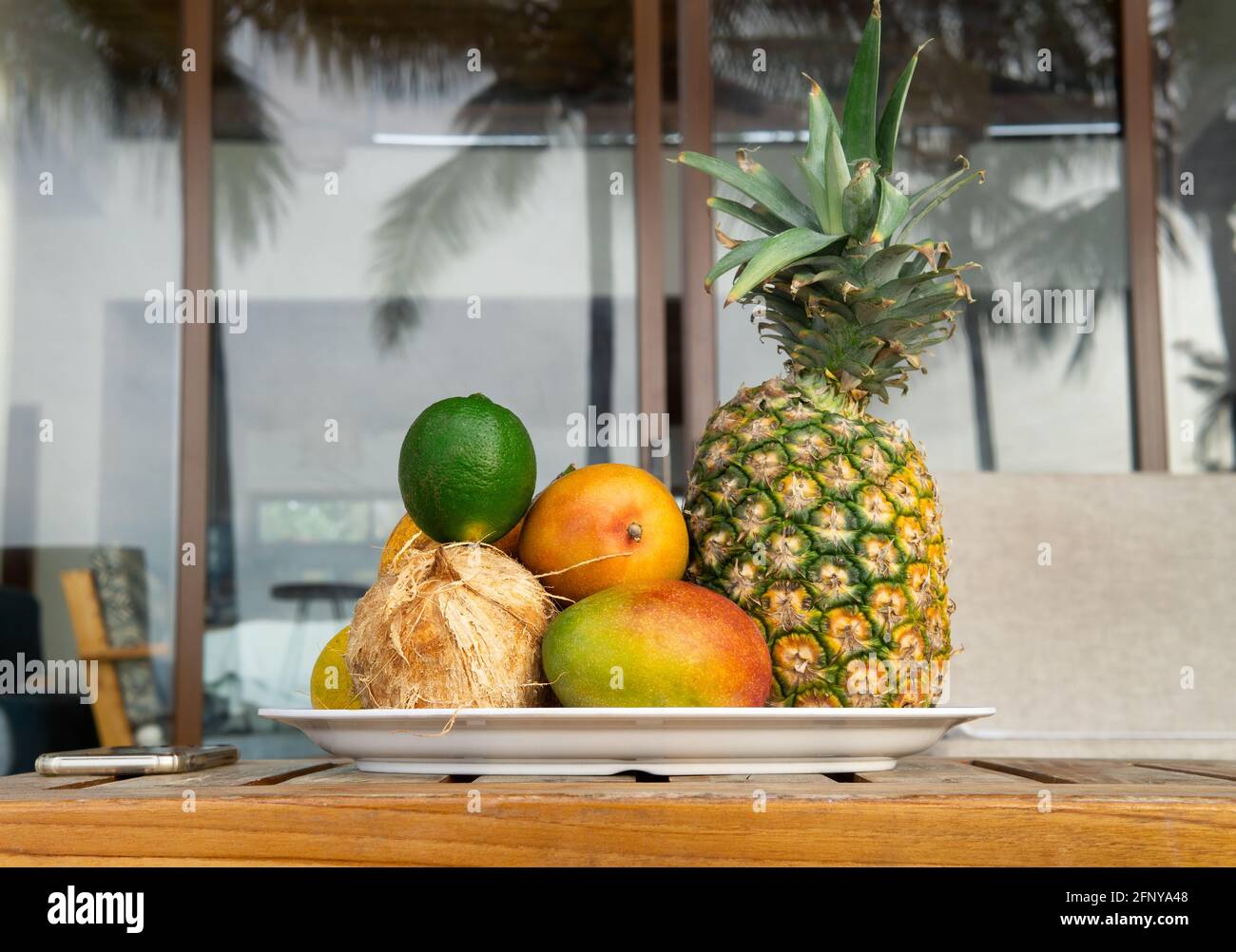 Close-up of a plate of tropical fruits on a wooden table with palm ...