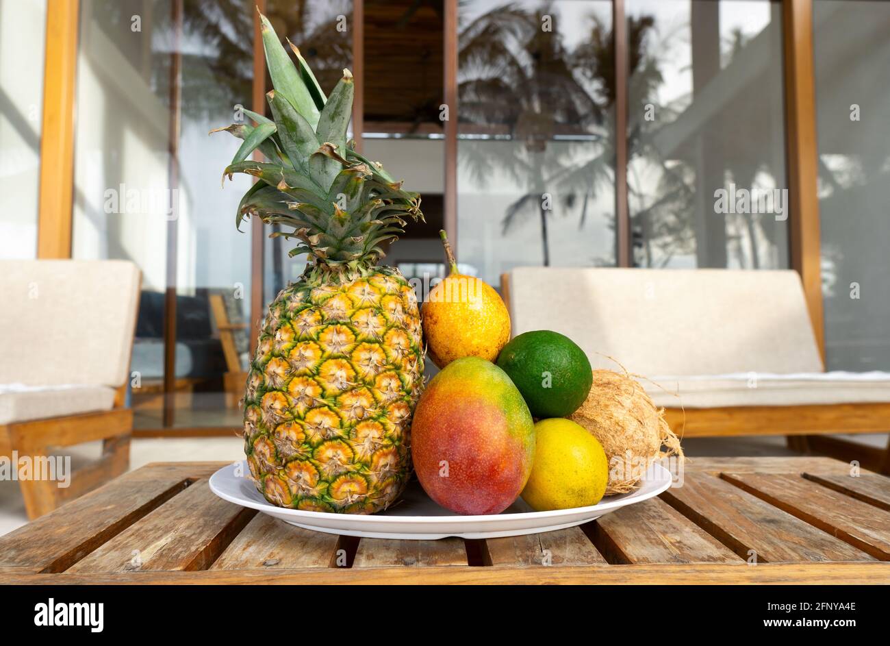 A plate of tropical fruits on a wooden table with palm trees ...
