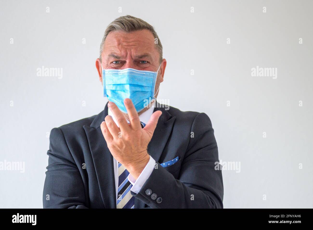Troubled businessman in suit and face mask trying to explain his point ...