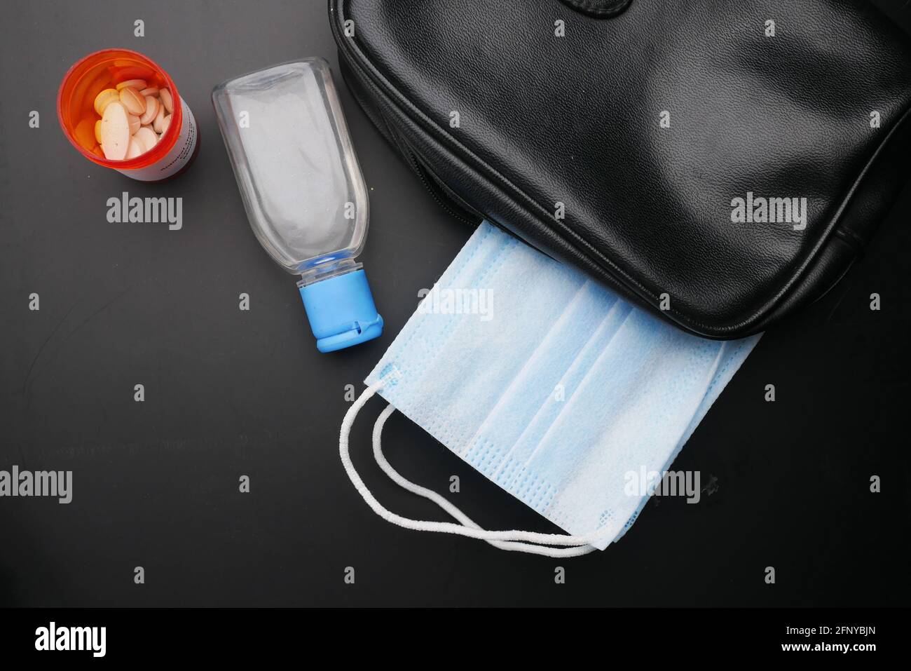 Surgical masks, pill container and hand sanitizer on black background ...