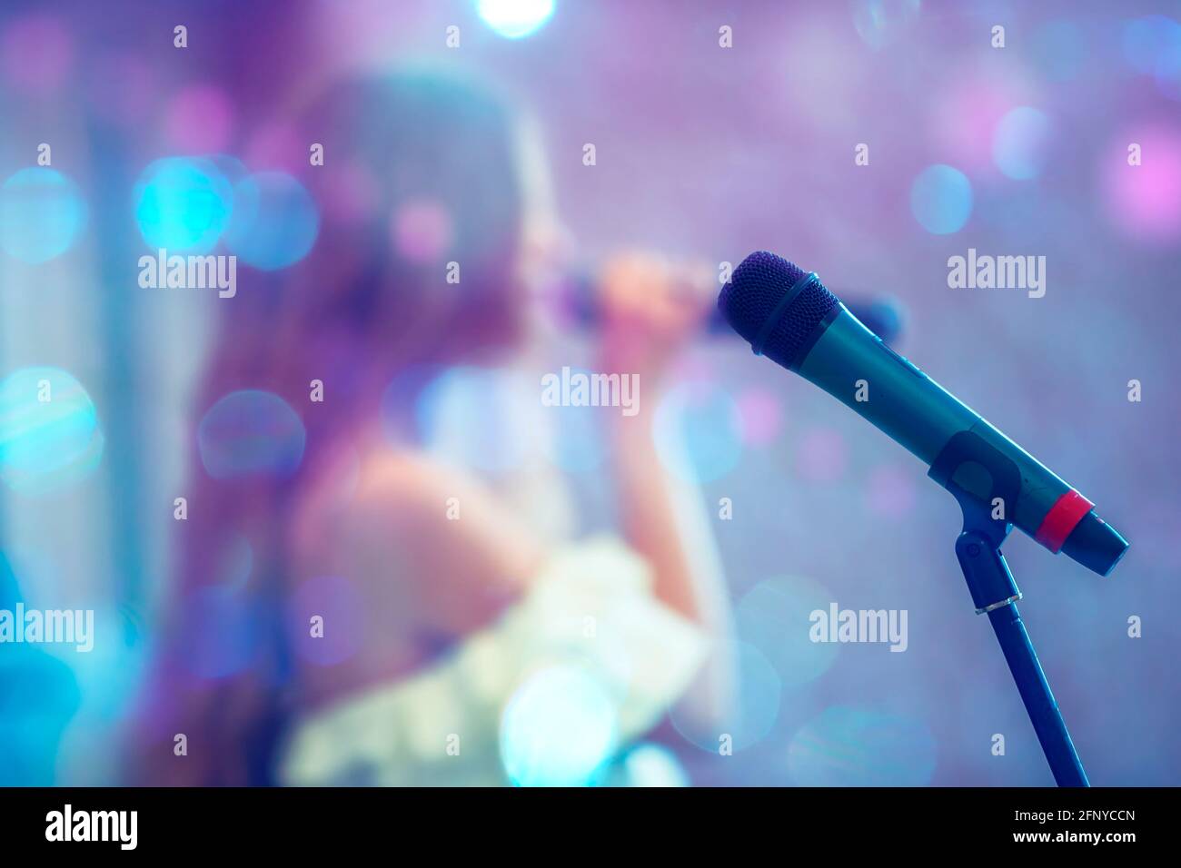 Stage microphone against the background of a blurred singer in spots of ...