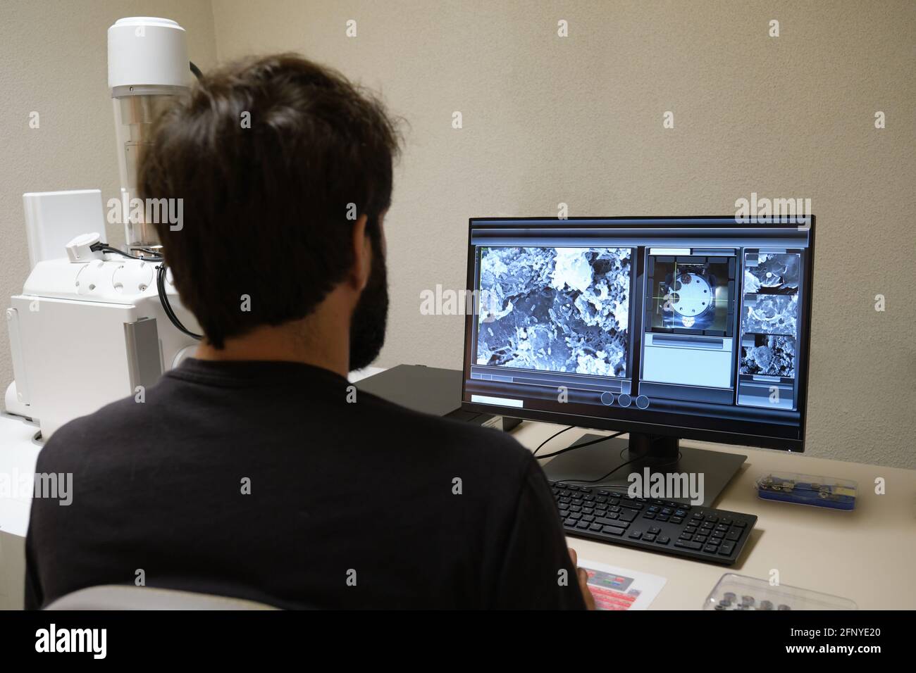Young man scientist working with scanning electron microscope ...
