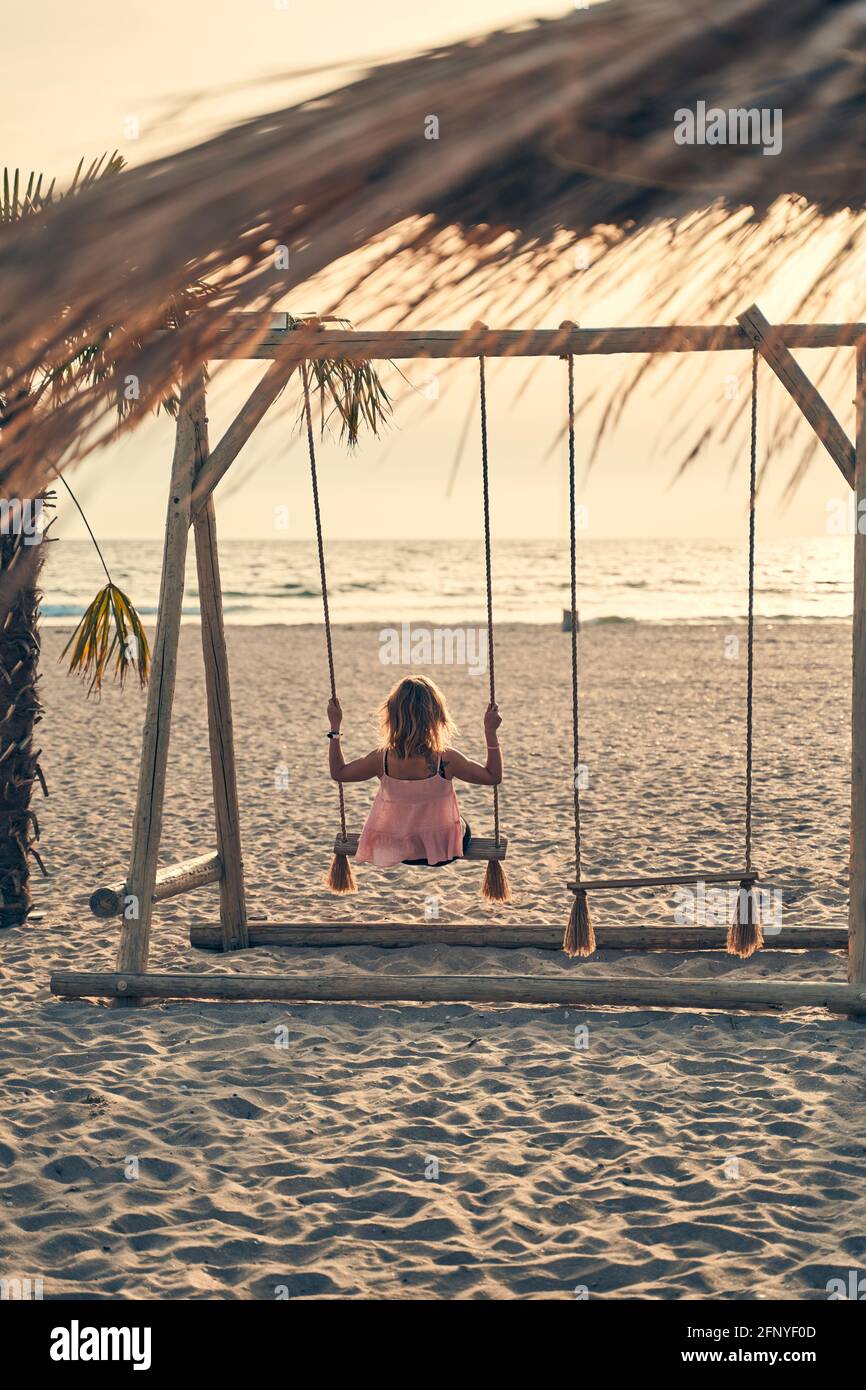 Young attractive woman swinging on seesaw on the beach. Summertime ...