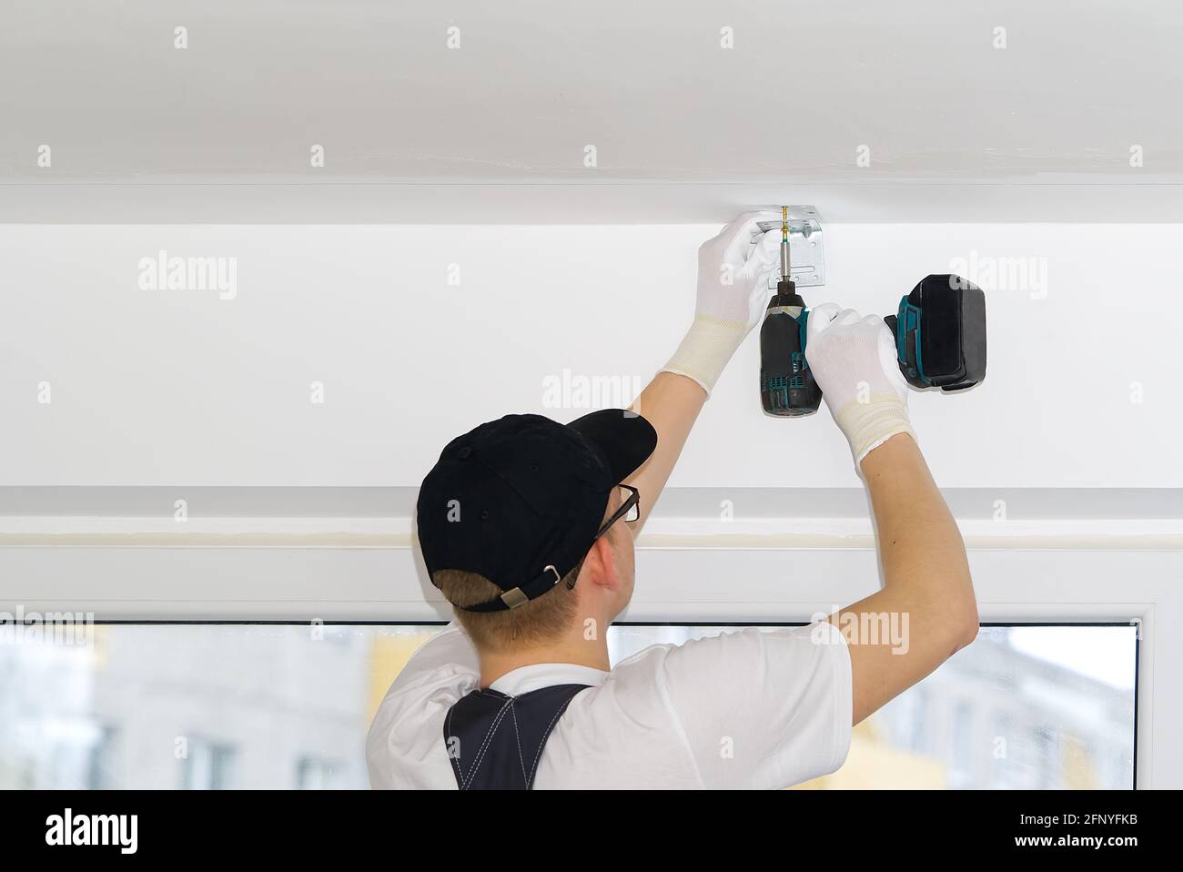 the master screws the metal corner to the concrete ceiling using a ...