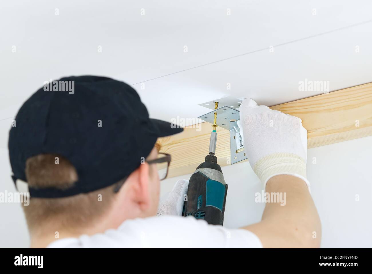 the master screws the metal corner to the concrete ceiling using a ...