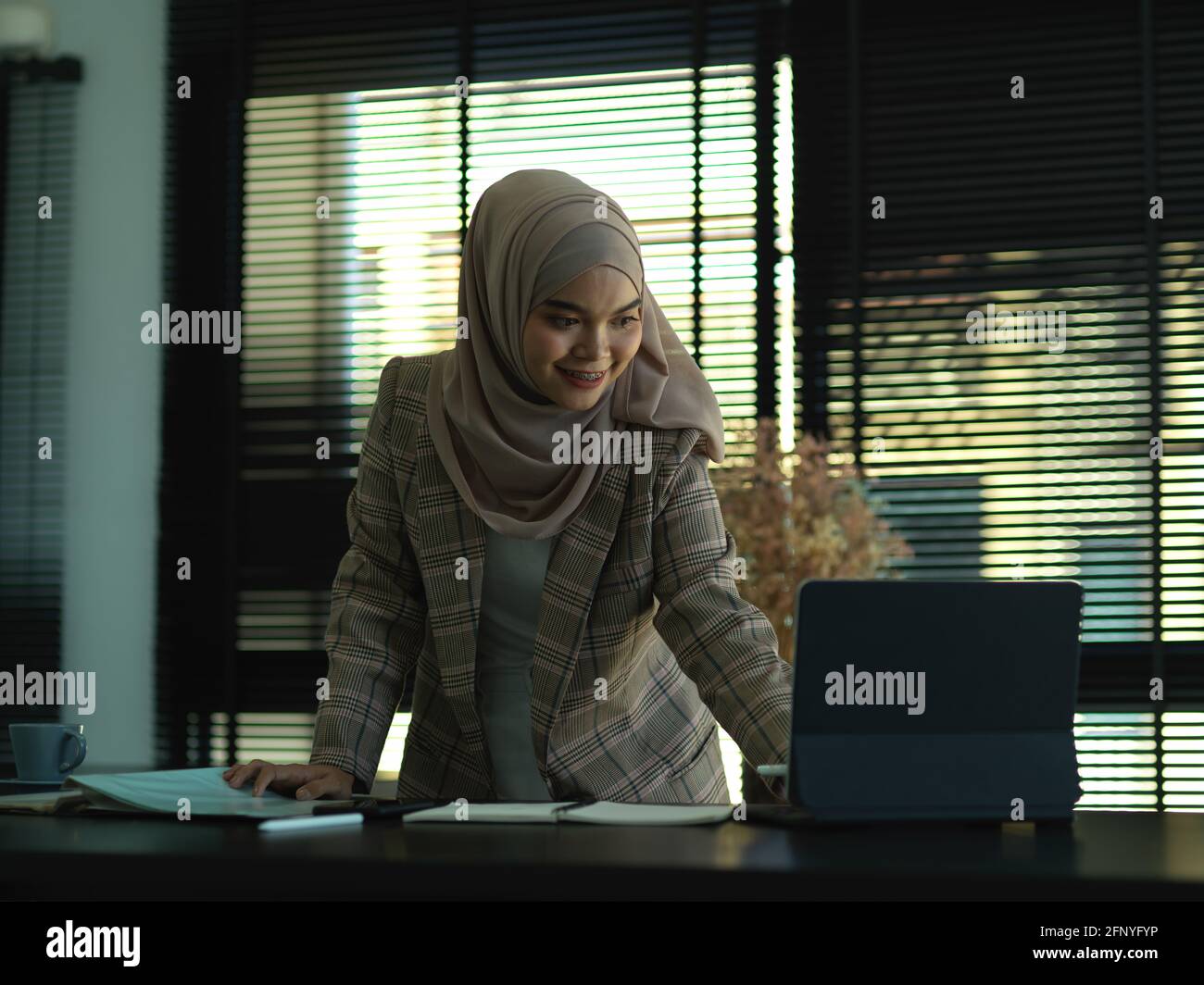 Portrait of young muslim working with tablet while standing in office ...