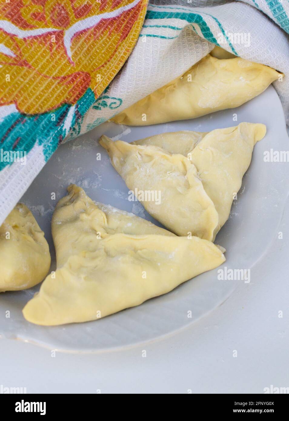 A few raw sambus on a white plate, before baking in a tandoor ...