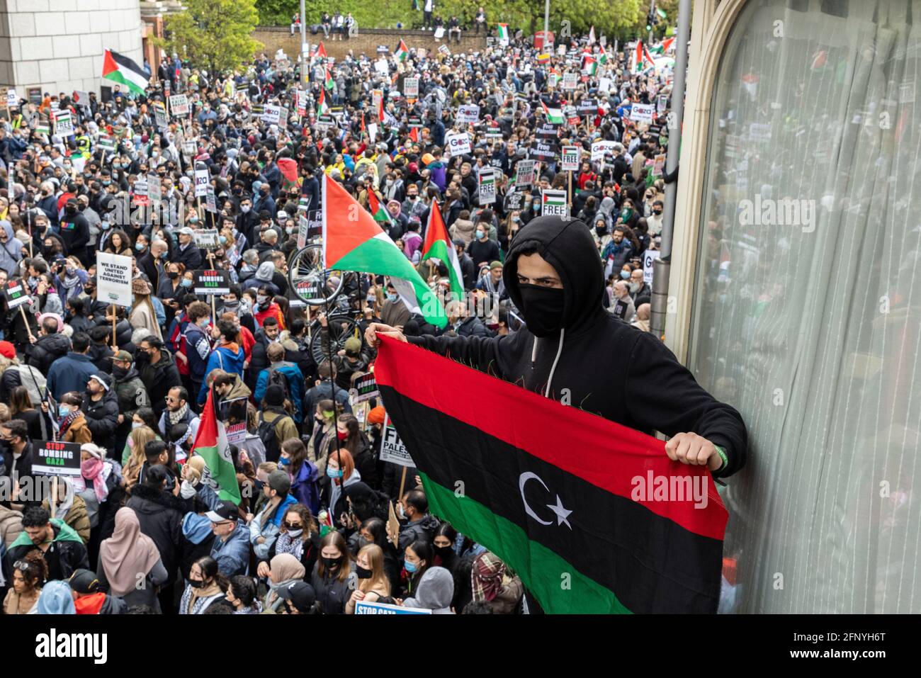 Masked protester holds flag above crowd, 'Free Palestine' solidarity ...