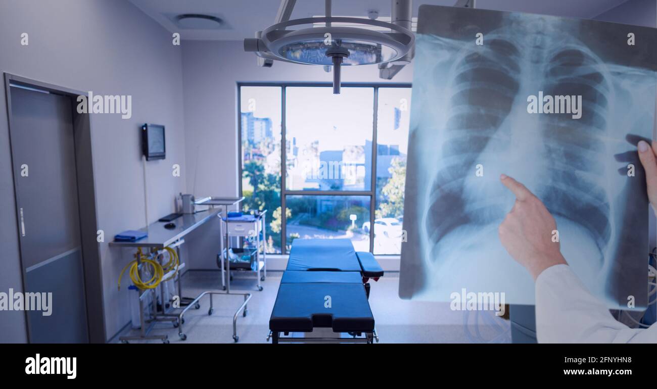 Mid section of doctor examining x-ray report against operation theatre ...