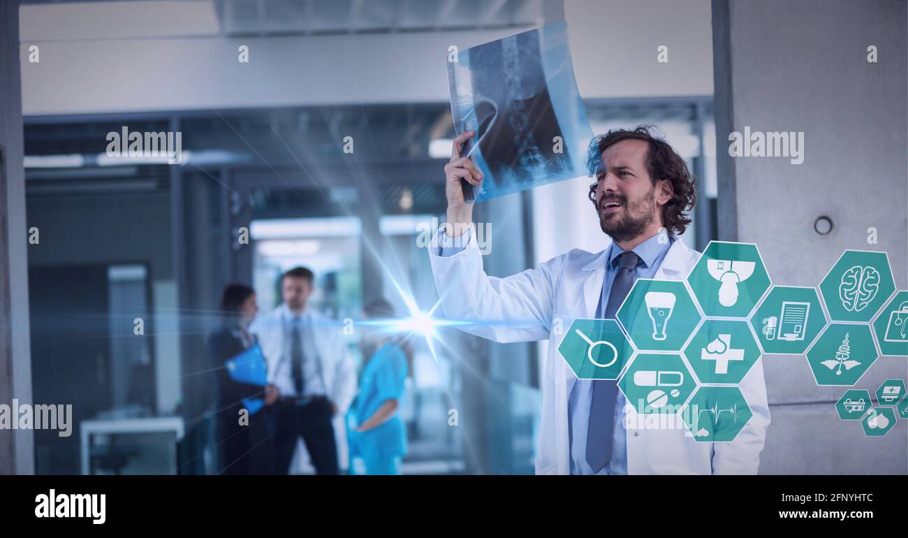 Spot of light and multiple medical icons against male doctor examining ...