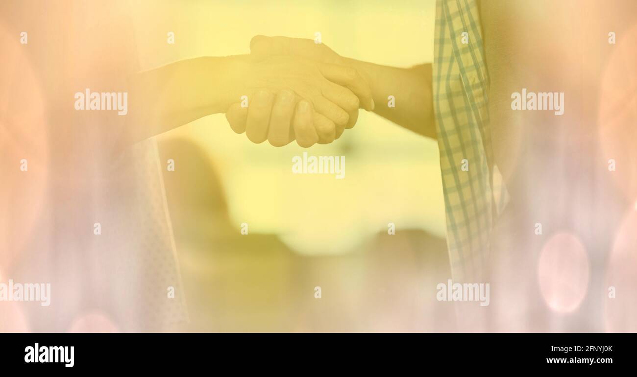 Composition of handshake with glowing yellow spots of light Stock Photo ...