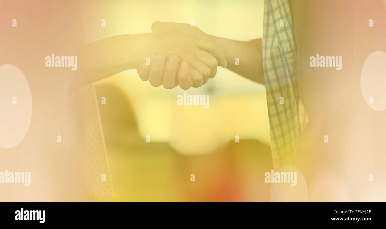 Composition of handshake with glowing yellow spots of light Stock Photo ...