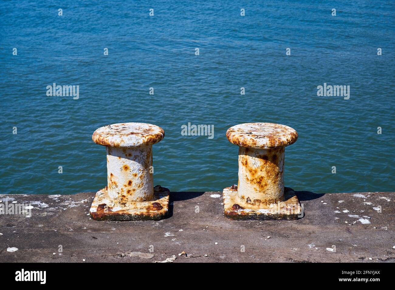 Two pillar bollards for mooring boats on a harbour wall Stock Photo - Alamy