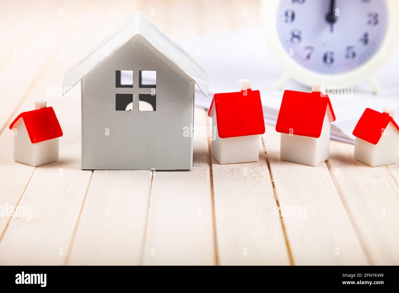 Small houses and clock on a wooden background. Time to buy for real ...