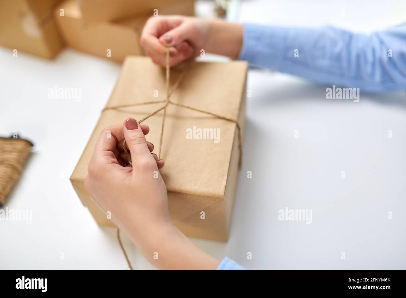 hands packing parcel and tying rope at post office Stock Photo - Alamy
