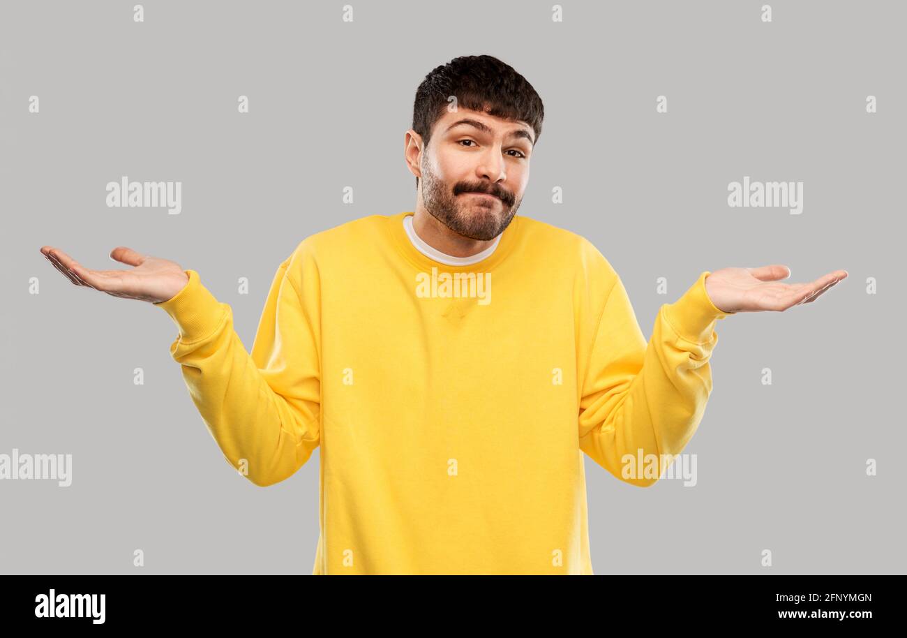 confused man in yellow sweatshirt shrugging Stock Photo - Alamy