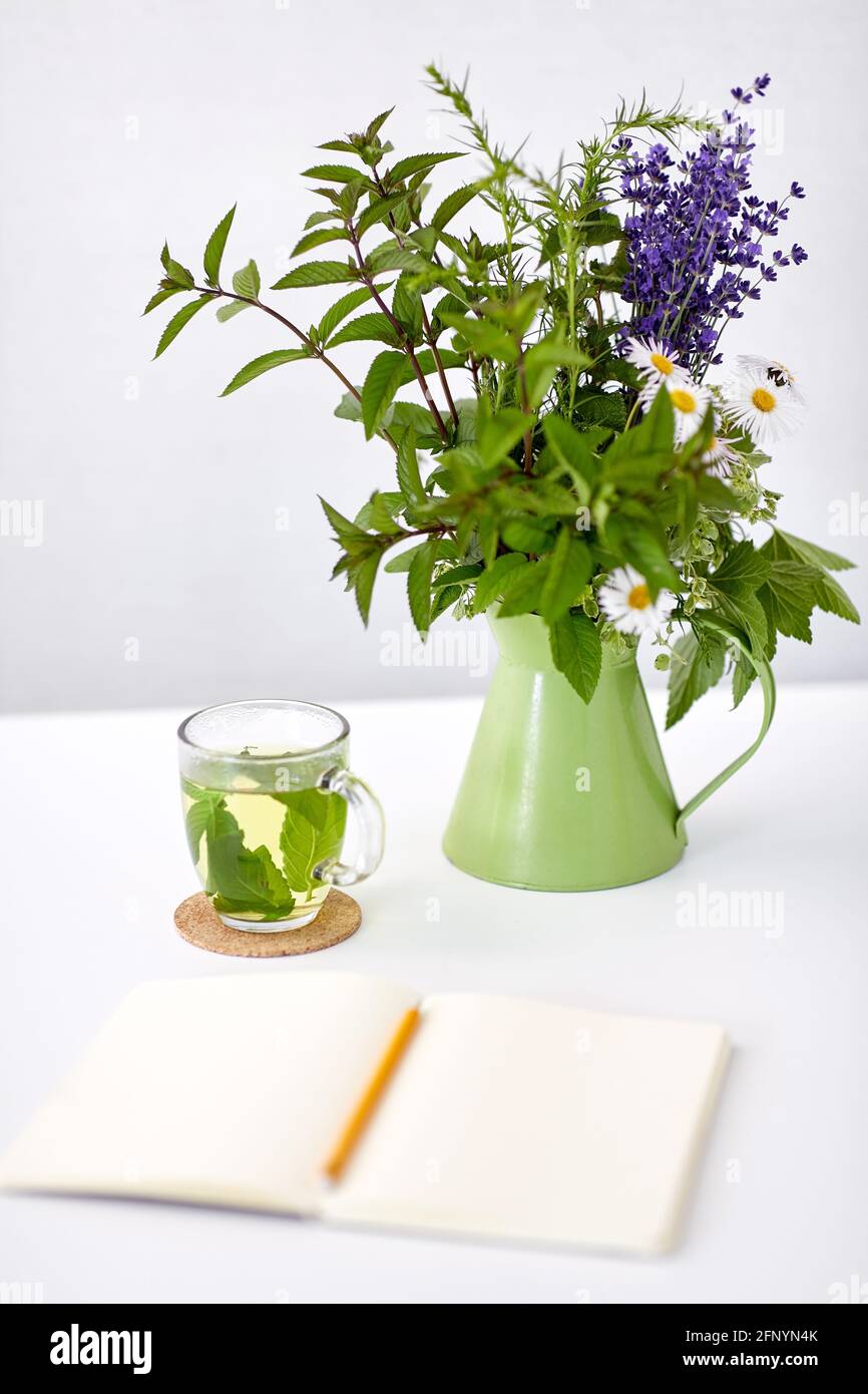 herbal tea, notebook and flowers in jug on table Stock Photo - Alamy
