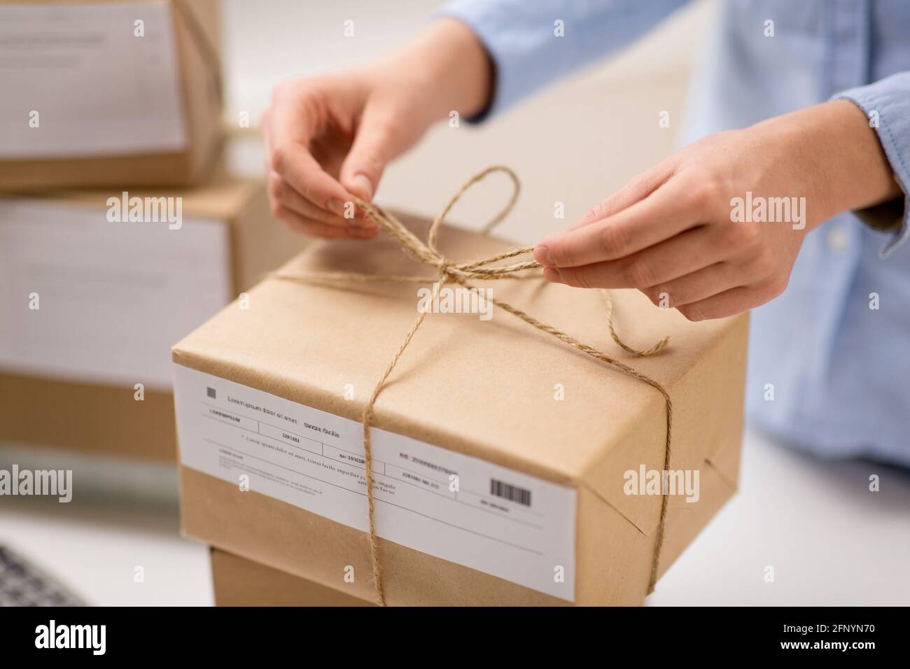 woman packing parcel and tying rope at post office Stock Photo - Alamy