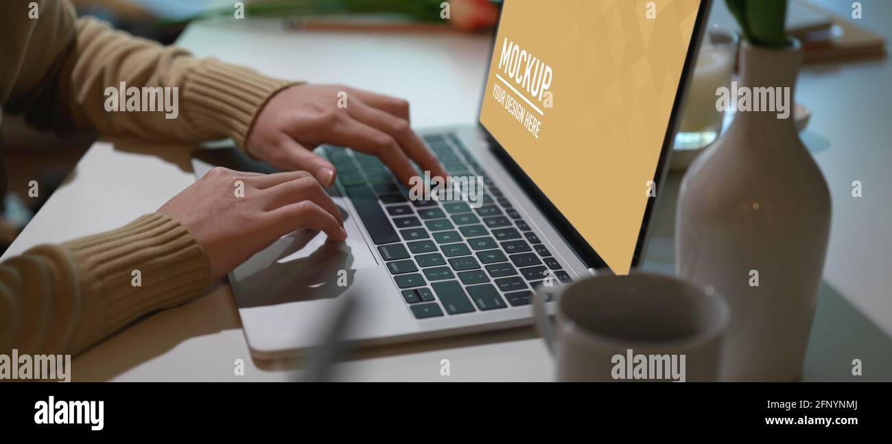 Side view of female hands typing on laptop keyboard on white worktable ...