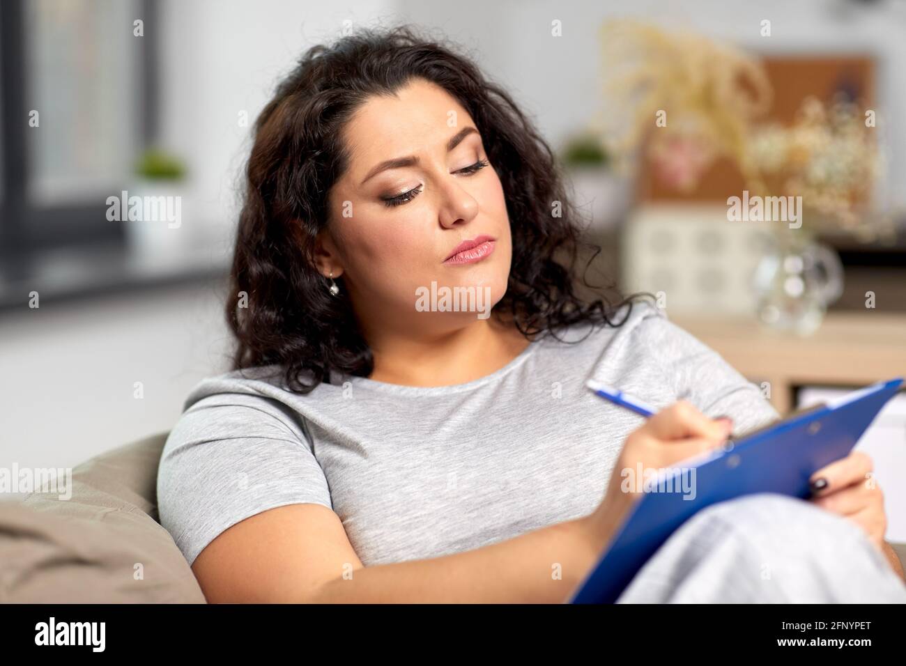 young woman with clipboard taking notes at home Stock Photo - Alamy
