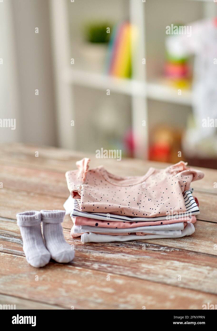 baby clothes on wooden table at home Stock Photo - Alamy