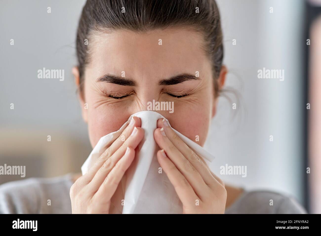 sick woman blowing nose in paper tissue at home Stock Photo - Alamy