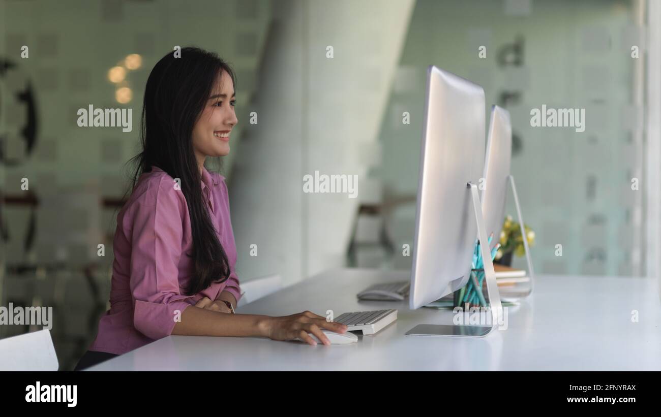 Side view of female office worker working with computer and office ...