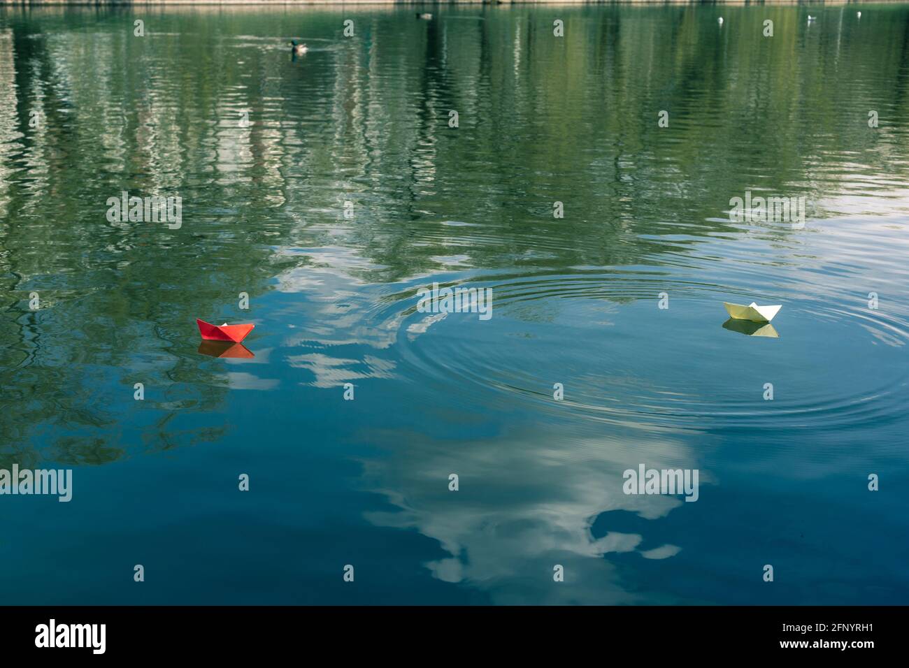 Red and white paper boats float on the water Stock Photo - Alamy