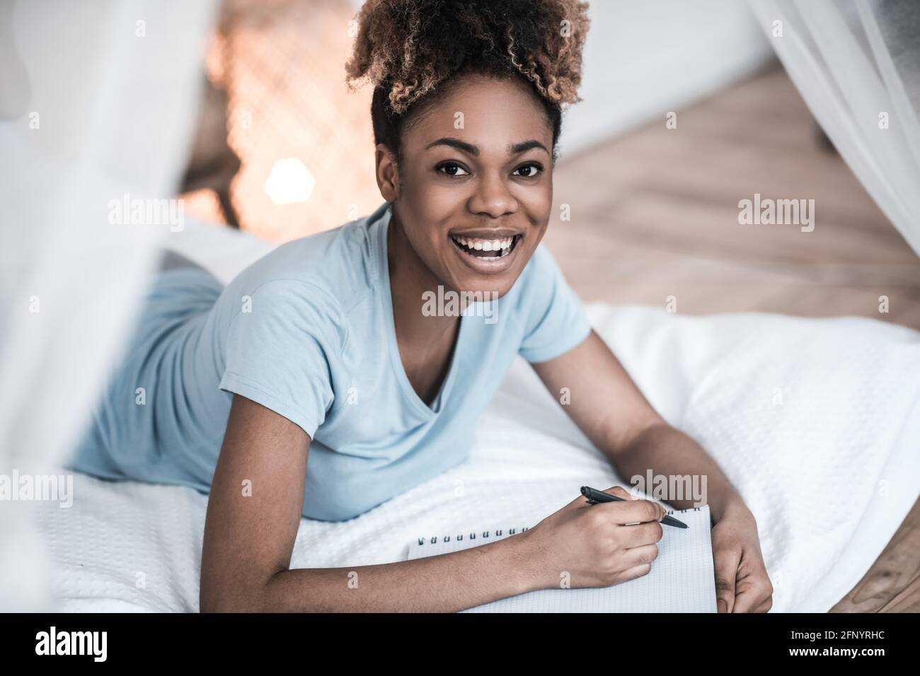 Beautiful woman writing notes while lying on bed Stock Photo - Alamy