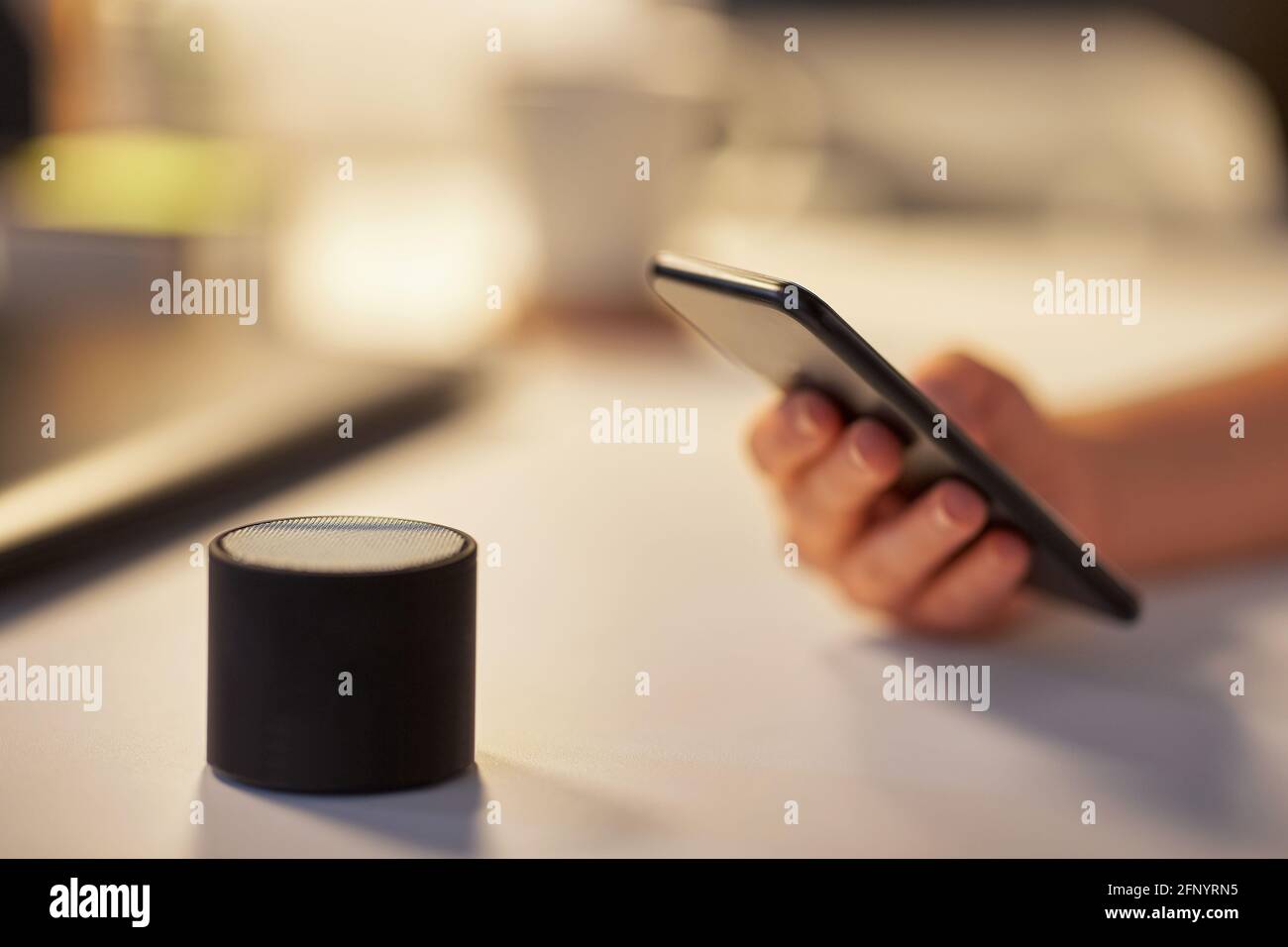 hand with smartphone and smart speaker at office Stock Photo - Alamy
