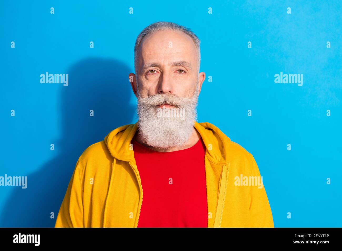 Photo portrait of serious old man wearing hoody isolated on bright blue ...
