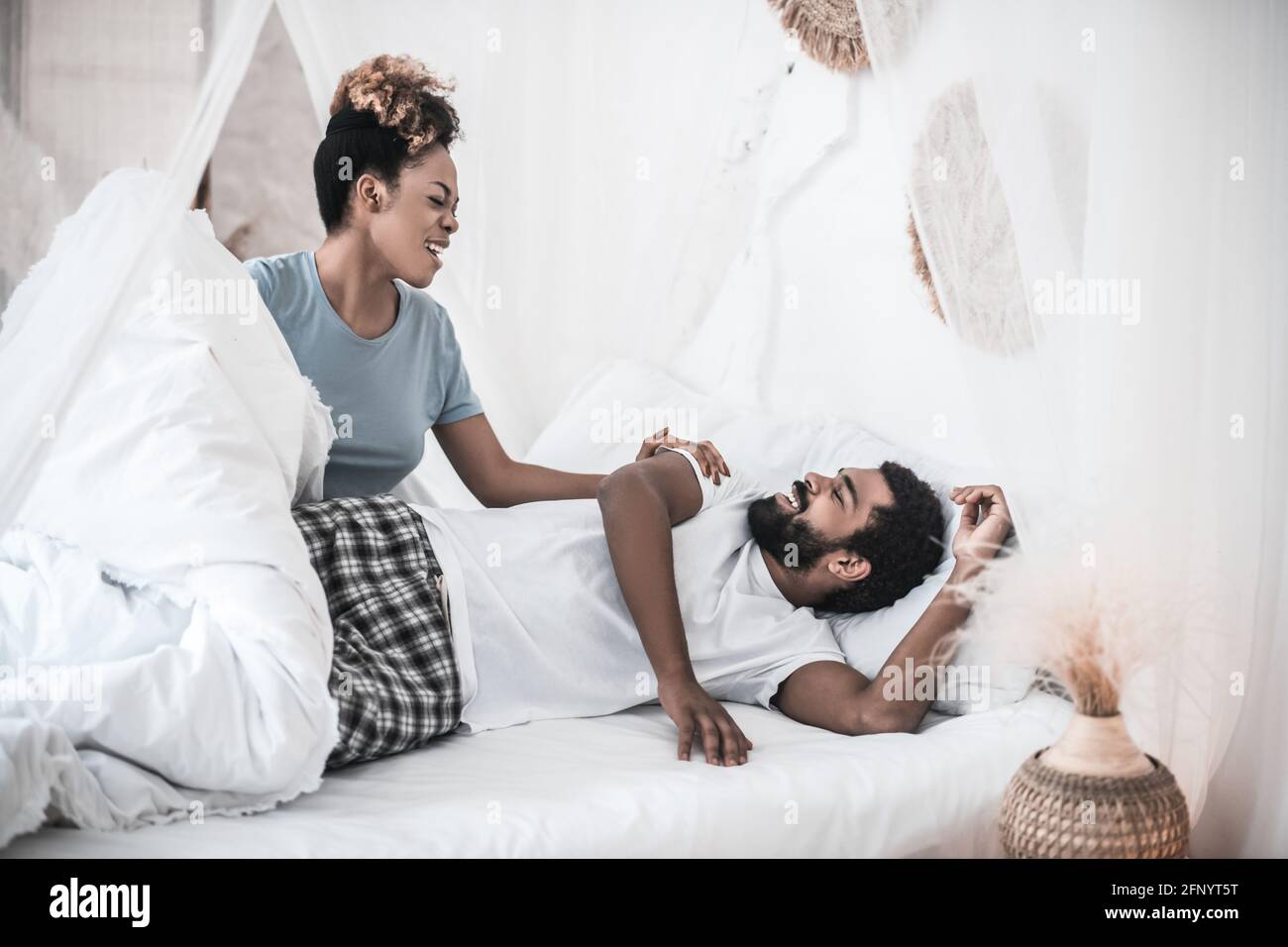 Woman taking blanket from sleepy man Stock Photo - Alamy