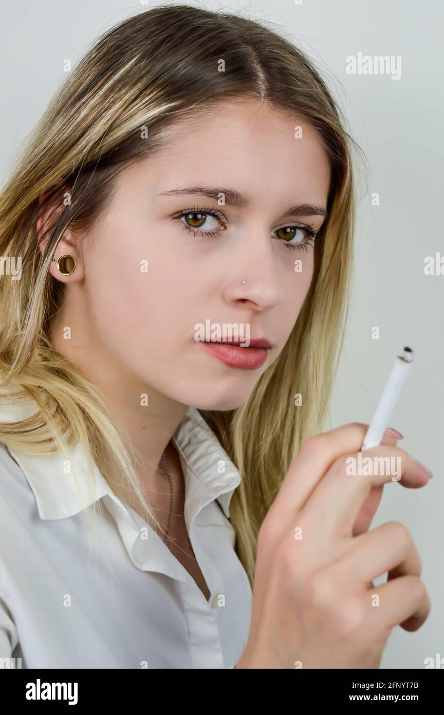 Portrait of a beautiful young blonde woman who is smoking a cigarette ...