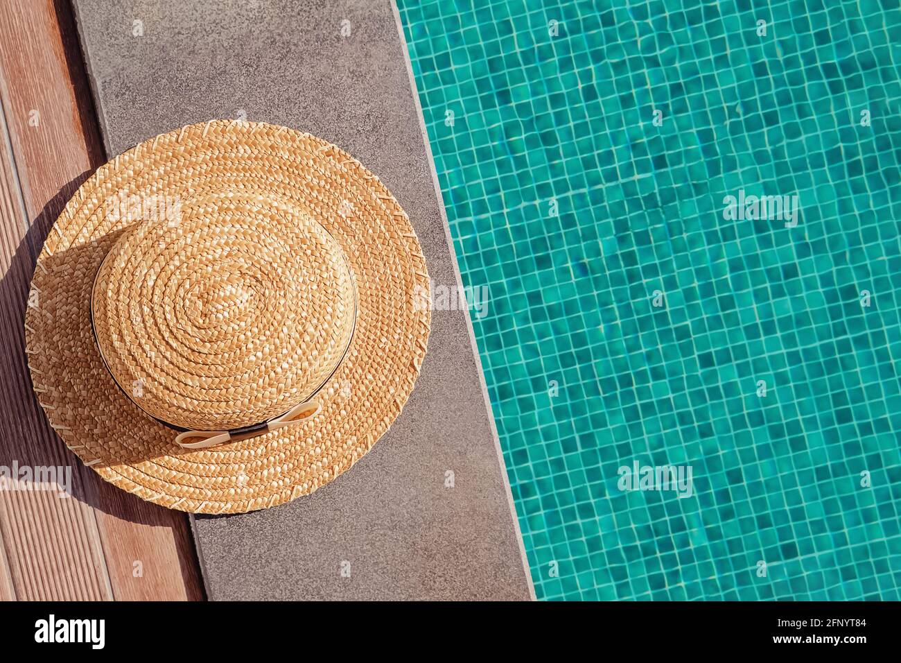 Woman's straw hat lying on the edge of the swimming pool with turquoise ...