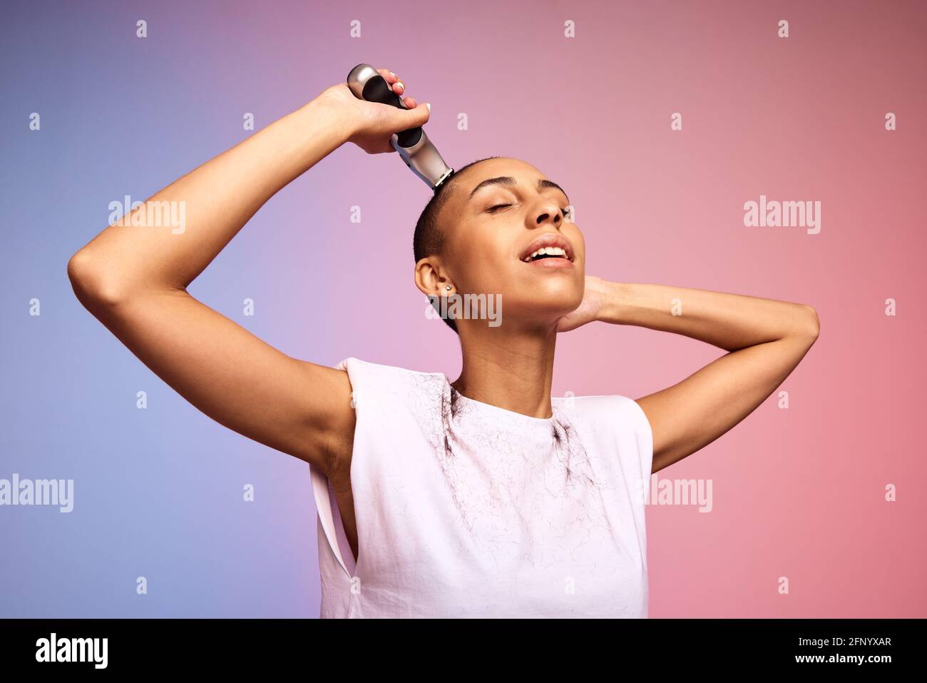 Strong female shaving her head using trimmer. Woman cutting her hair ...