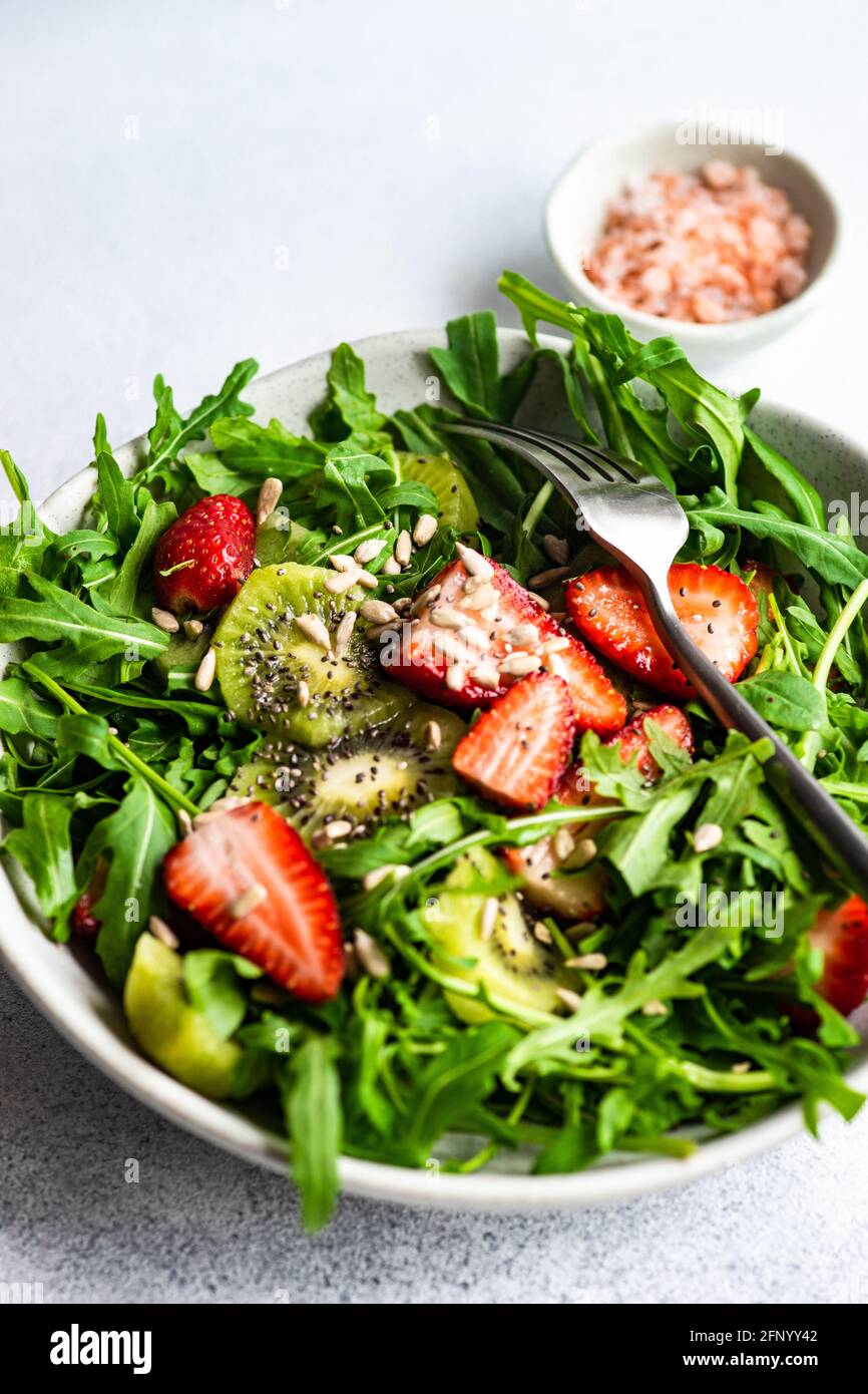 Overhead view of a bowl of rocket, strawberry and kiwi fruit salad with ...